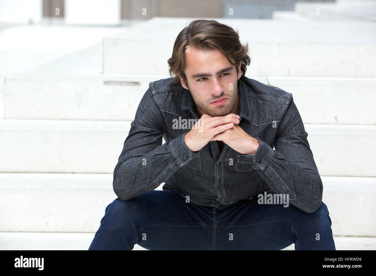 Portrait of a young man sitting on steps outside Stock Photo - Alamy