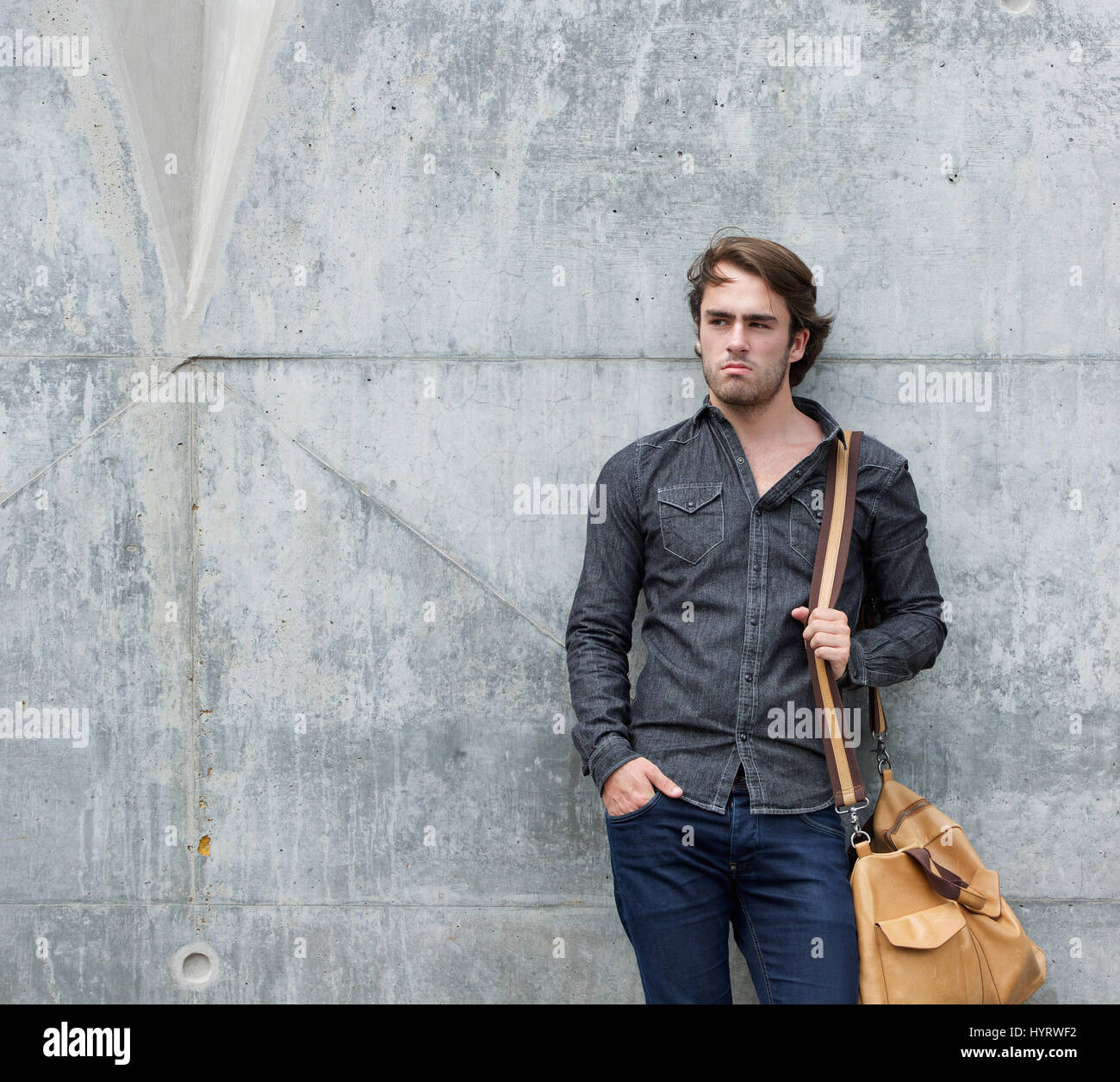 Portrait of a cool guy posing with leather travel bag outdoors Stock ...
