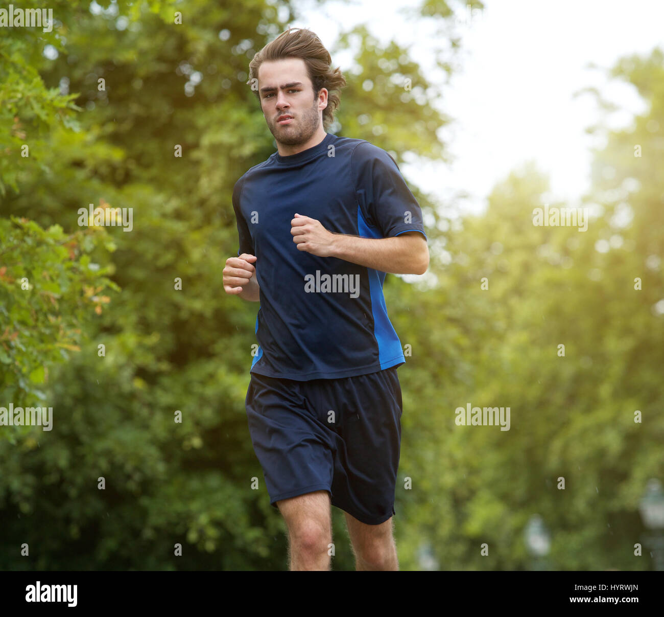 Young man jogging outdoors in the forest with sunlight Stock Photo - Alamy