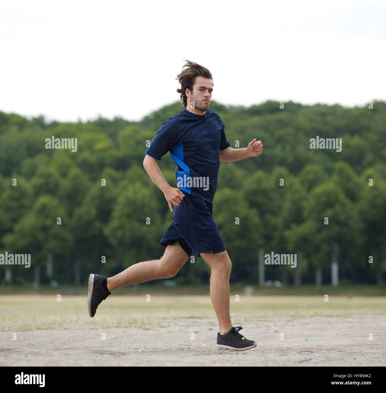 Full length side view of a young man running outside Stock Photo - Alamy