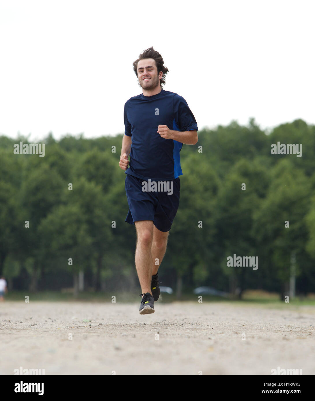 Active young man smiling and jogging outdoors Stock Photo - Alamy