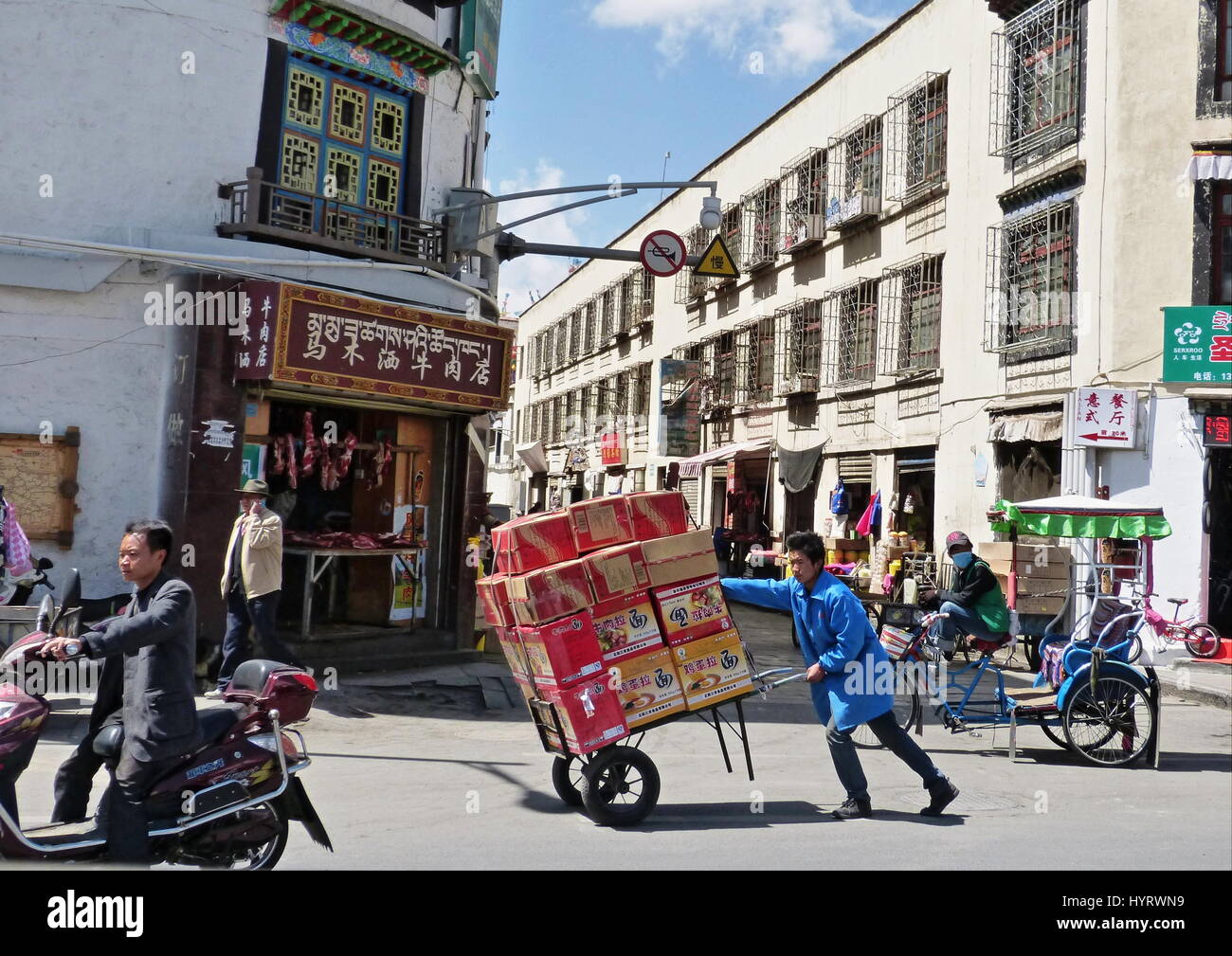 A street scene in Lhasa, Tibet with a vendor pushing his wares and ...