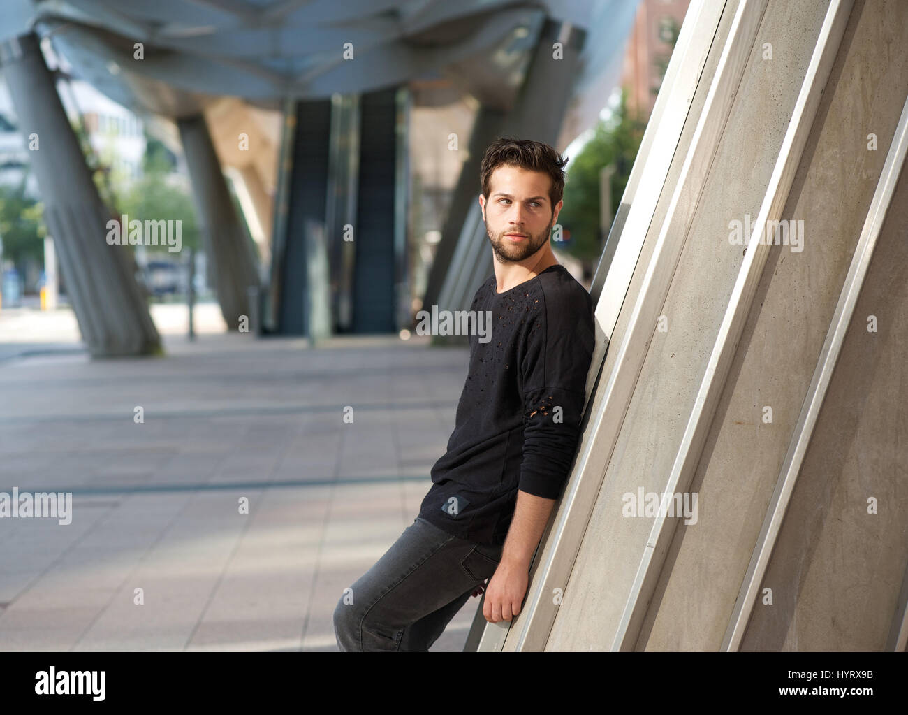 Side view portrait of a handsome male fashion model standing outdoors ...