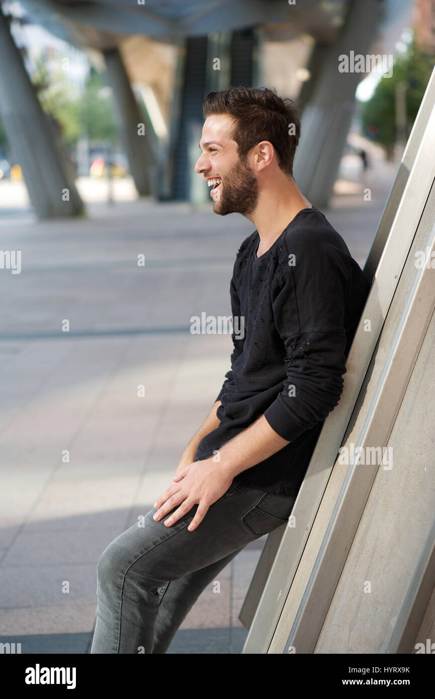 Side view portrait of a trendy young man smiling outdoors Stock Photo ...