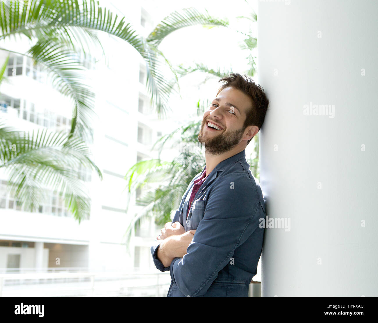 Close up portrait of a smiling man leaning with arms crossed inside ...
