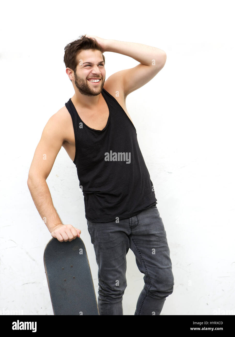 Portrait of a funky guy holding skateboard against white background ...
