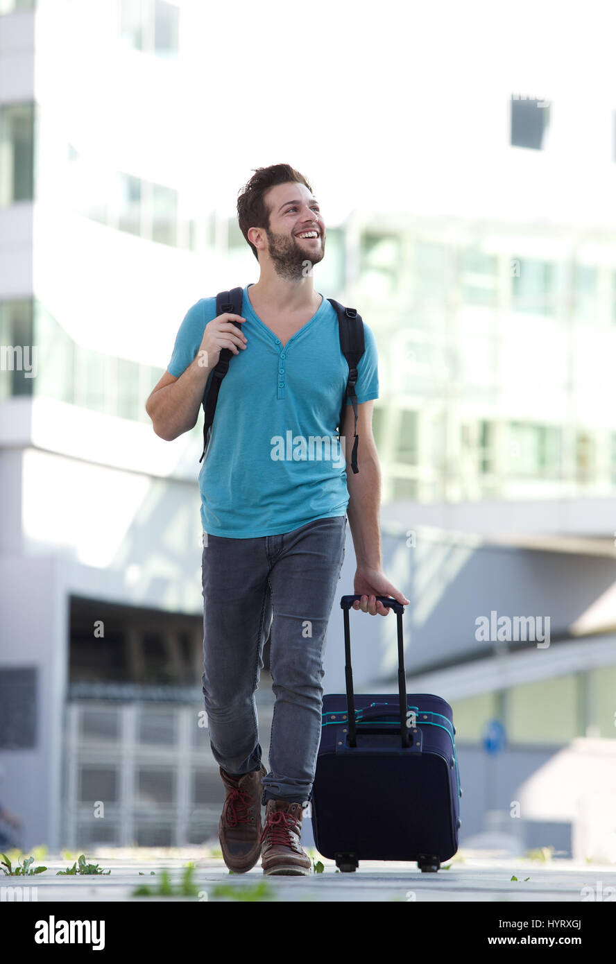 Portrait of a cool guy smiling with suitcase and bag in the city Stock ...