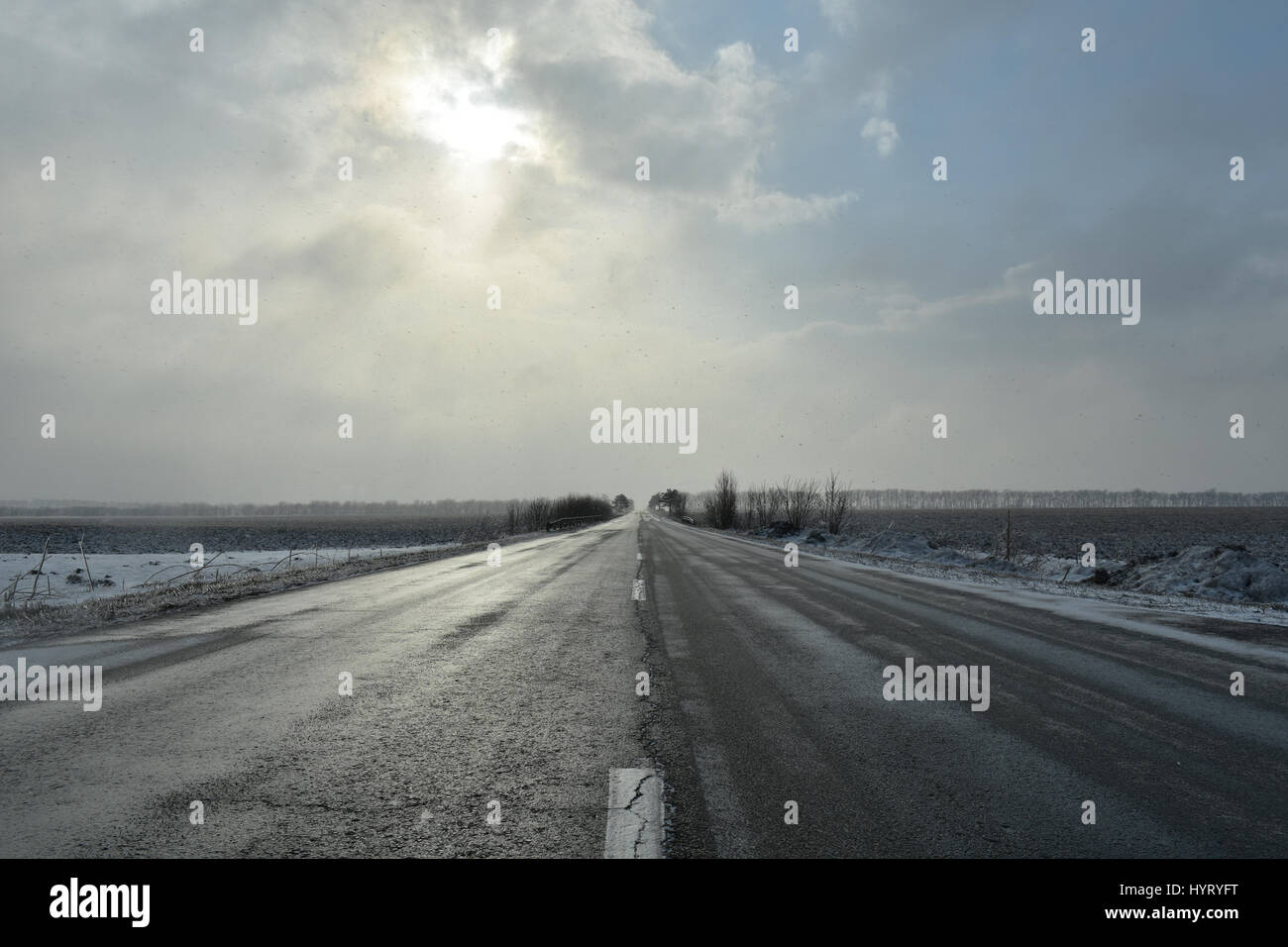 Reaching the horizon empty old asphalt country road in a flat field ...
