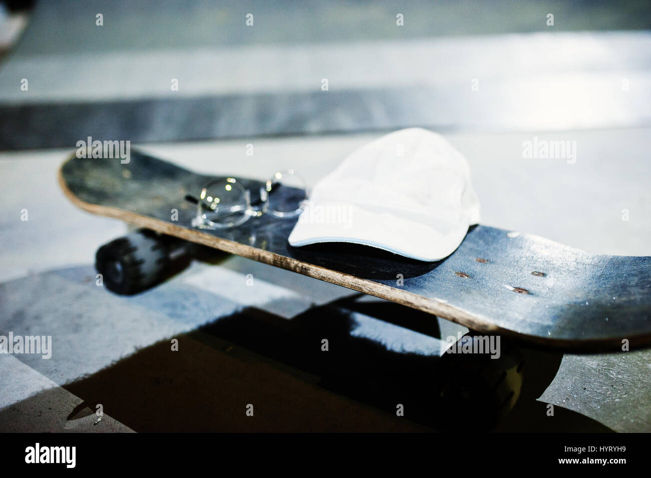 Skateboard with glasses and cap on skate park at evening Stock Photo ...
