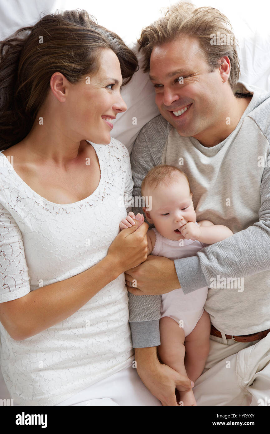Close up portrait of a smiling man and woman hugging baby in bed Stock ...