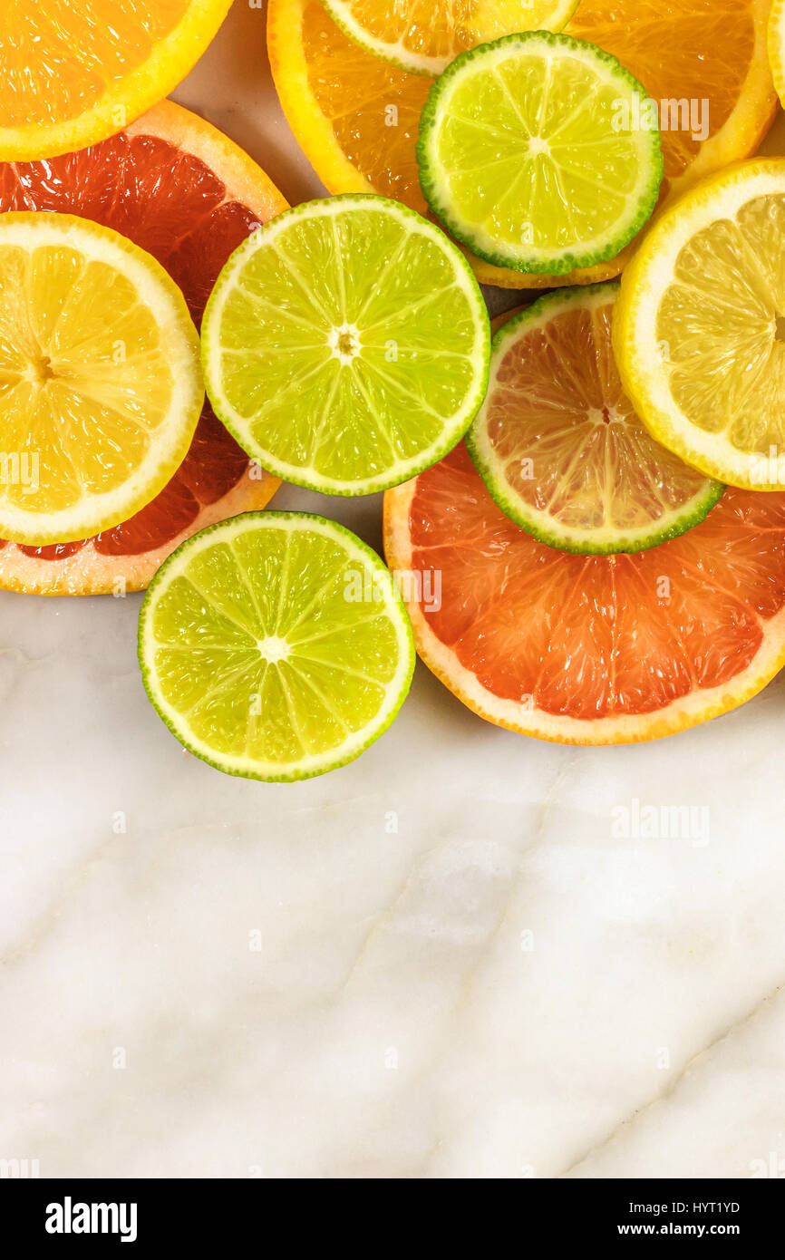 Vibrant juicy citrus fruits on a white marble texture with copy space ...