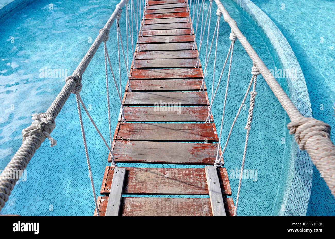 Small rope hanging bridge across the swimming pool in the free park for ...