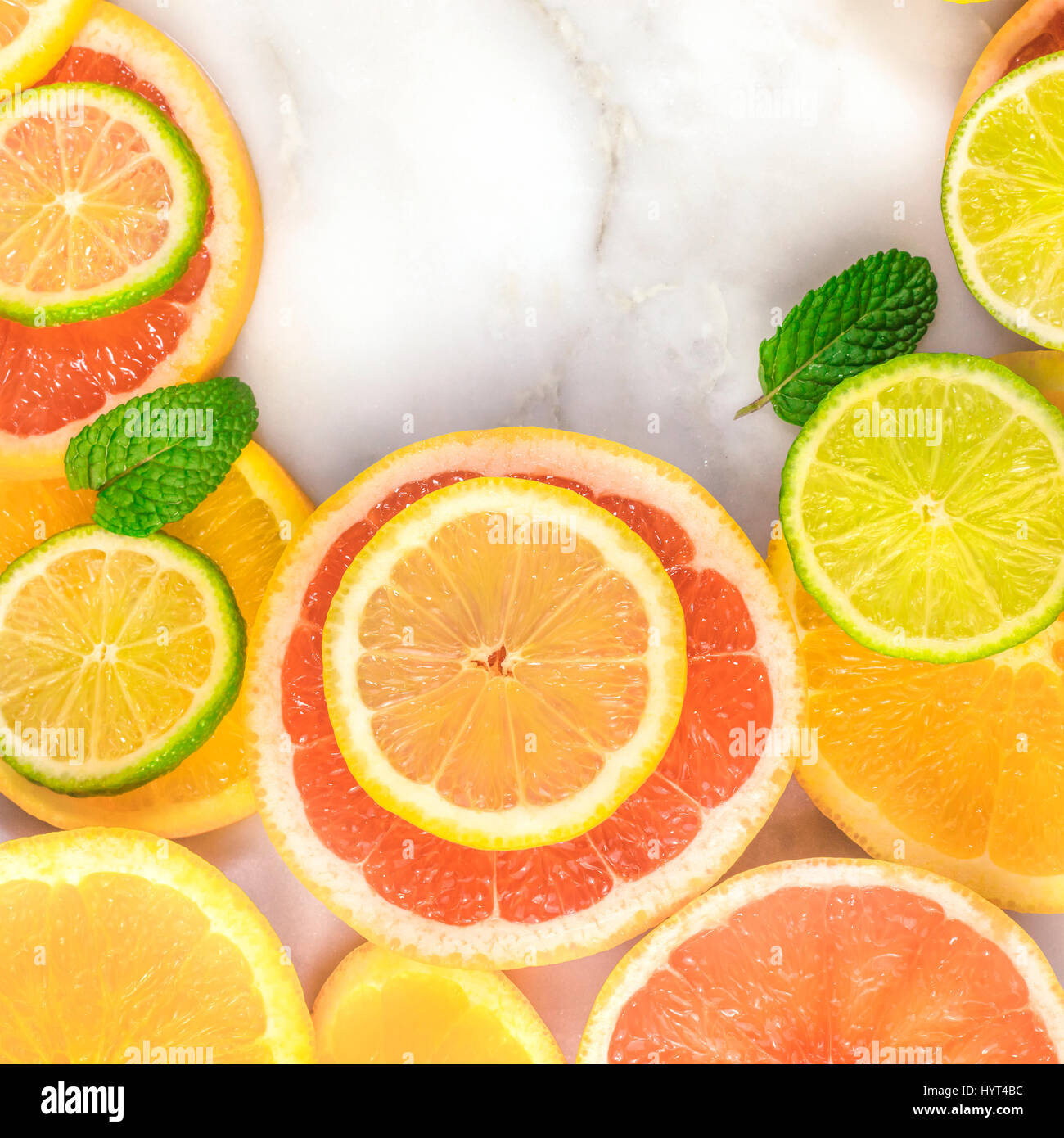 A square frame made up of juicy citrus fruits, on a white marble ...