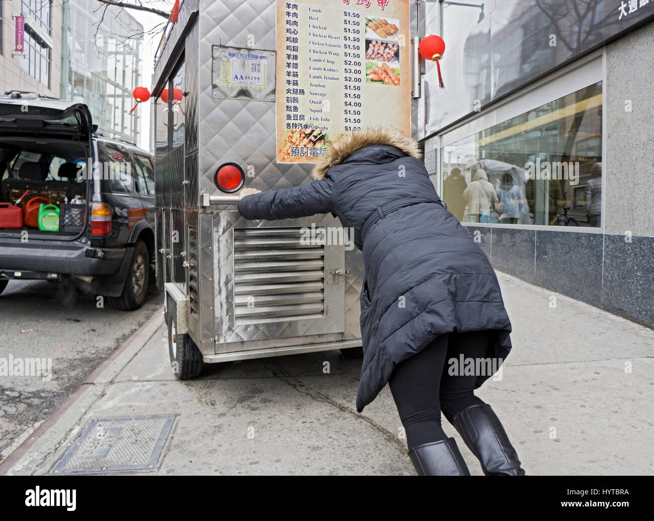 A Chinese American woman pushing a food cart into place on a street in ...