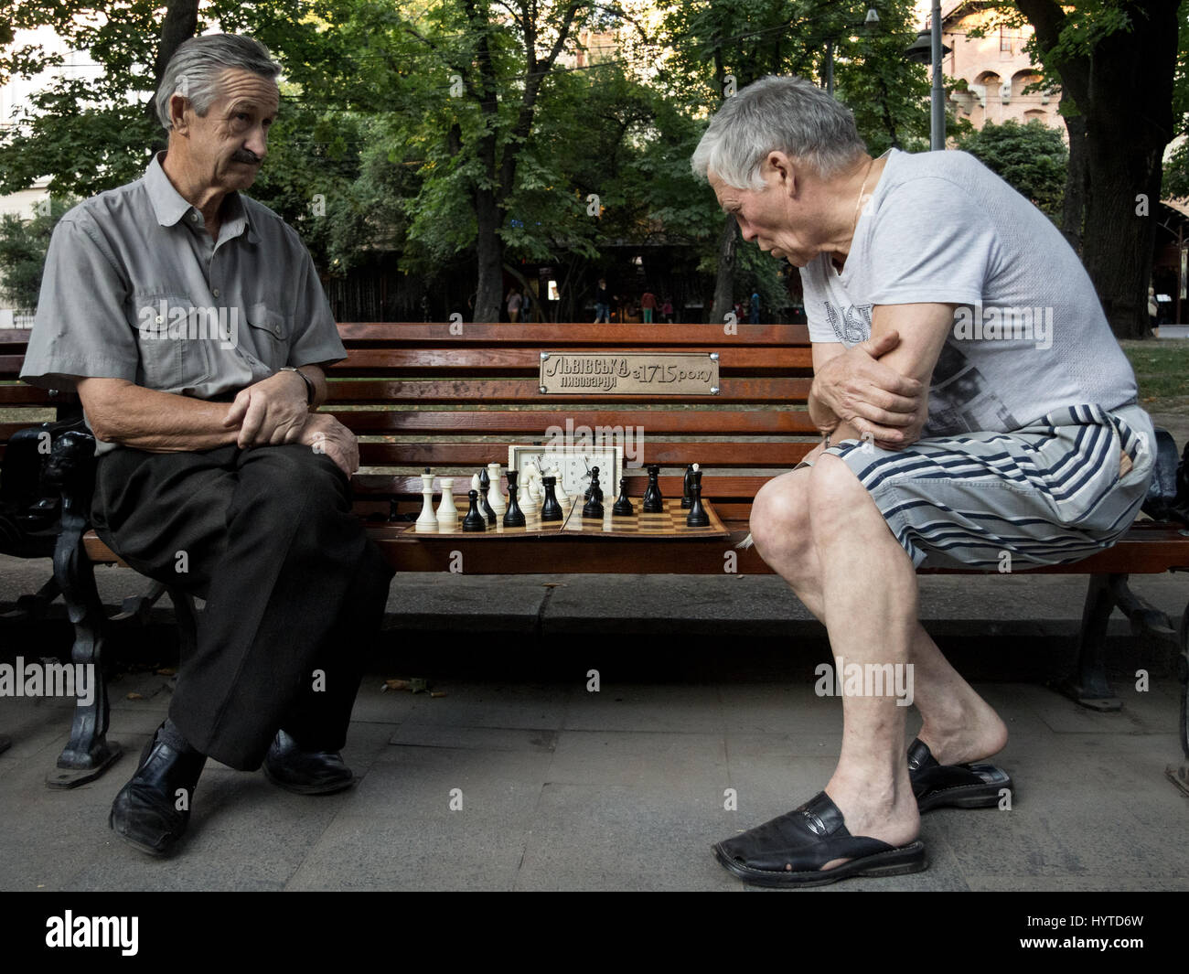 LVIV, UKRAINE - AUGUST 19, 2015: Old men playing chess on a bench in a ...