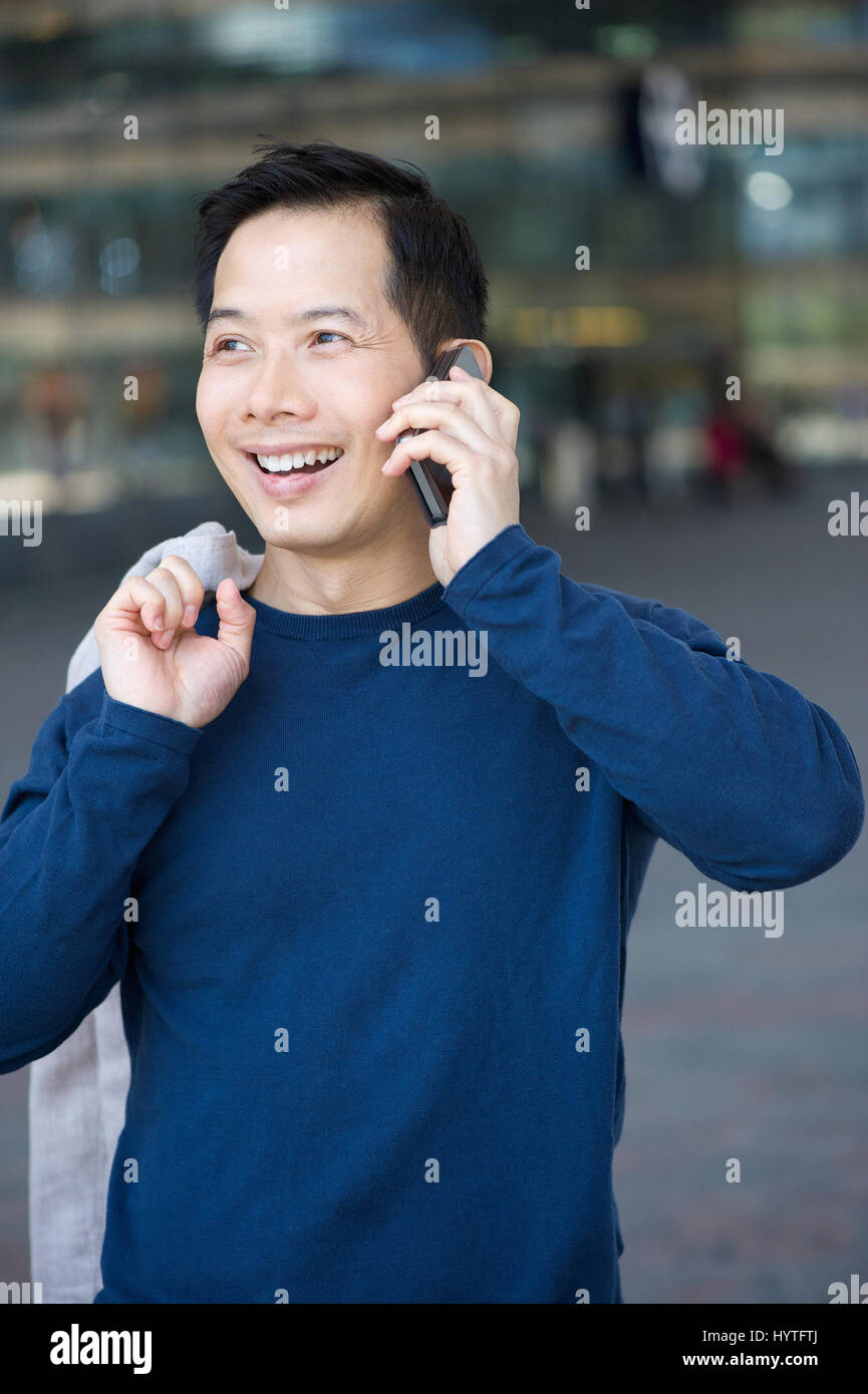 Close up portrait of a smiling asian man calling with mobile phone ...