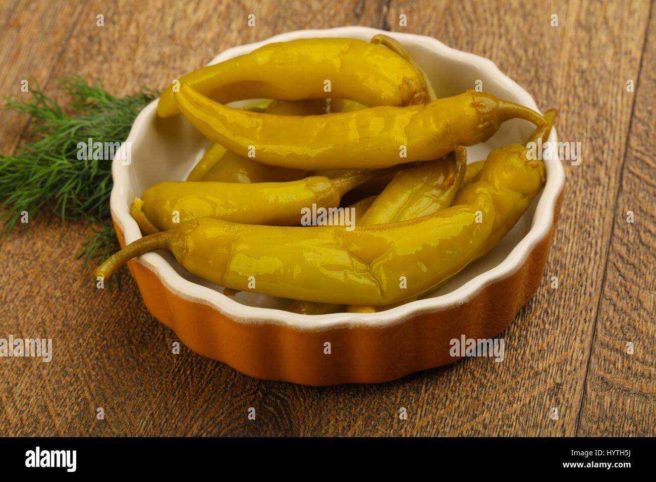 Pickled green pepperoni pepper in the bowl on wood background Stock ...