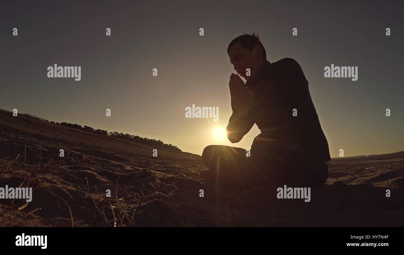 Man praying at sunset god sitting silhouette sun sunlight the religion ...