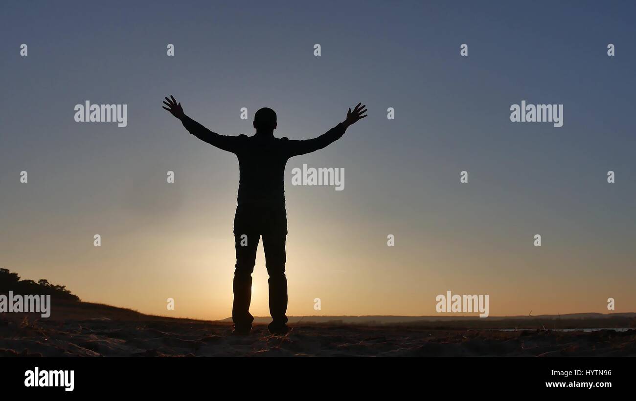 freedom. Man stands on a cliff sunset silhouette hand in lifestyle the ...