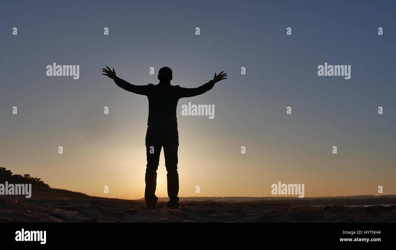 freedom. Man stands on a cliff sunset silhouette hand in lifestyle the ...