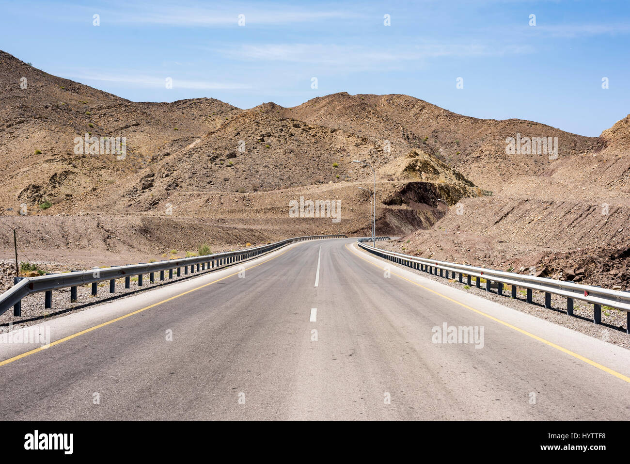 road in Oman meandering through wild, arid mountains and a wadi ...