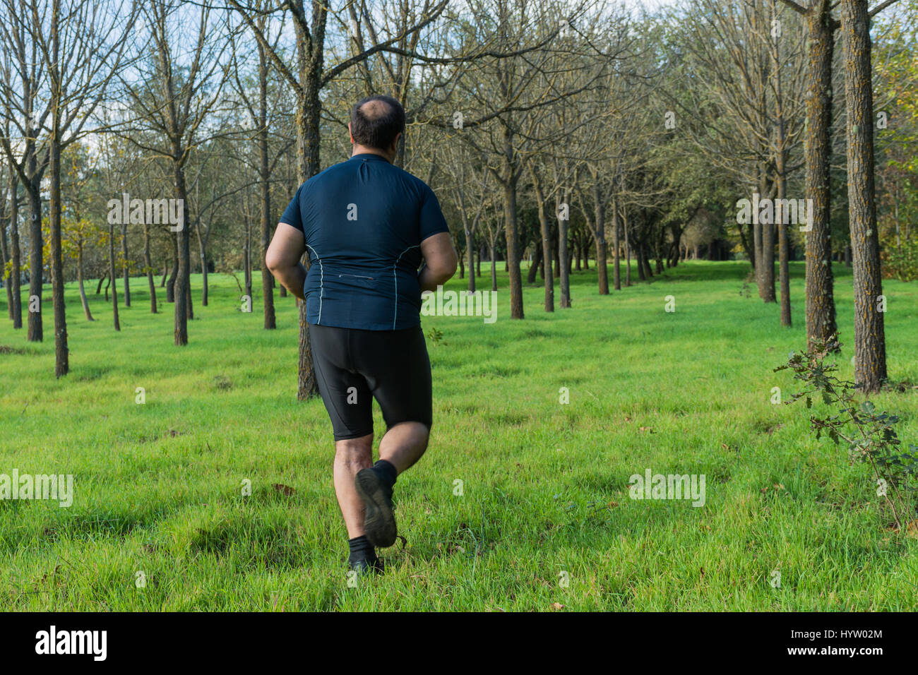 Big belly man jogging , exercising, doing cardio in the park , slightly ...