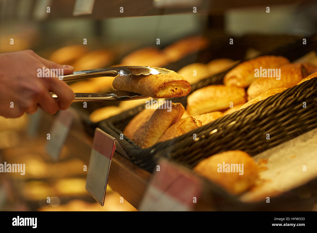 hand with tongs taking bun at bakery or grocery Stock Photo - Alamy