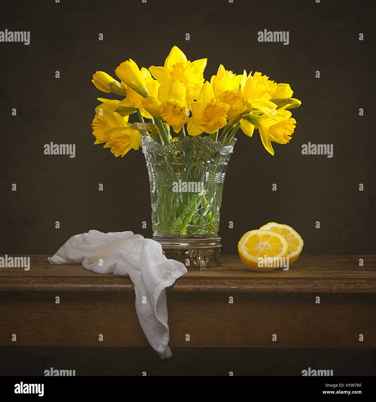 Bunch of spring daffodils with cut lemons still life on rustic table ...