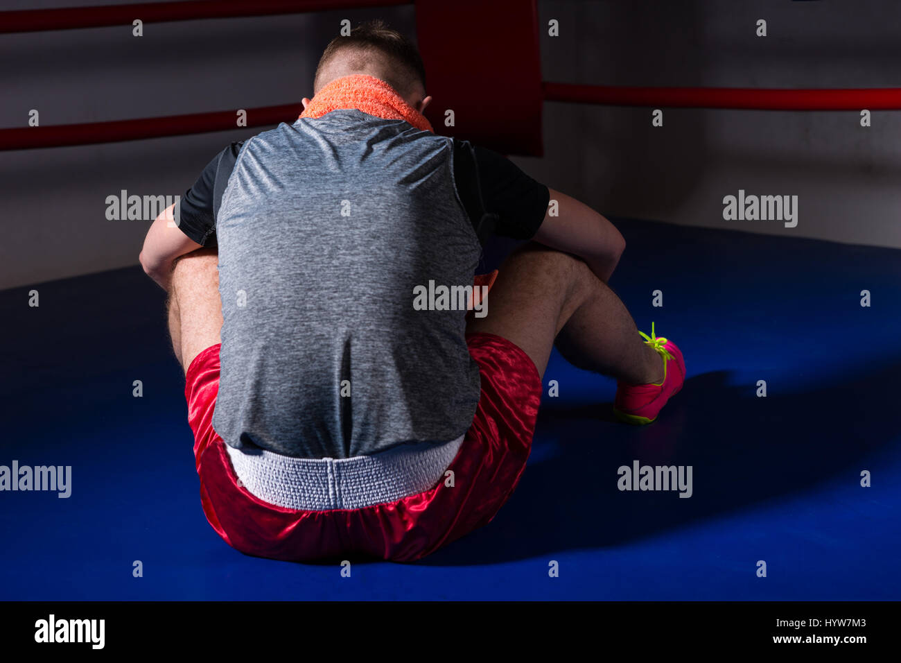 Young athletic male boxer sitting backwards in regular boxing ring in a ...