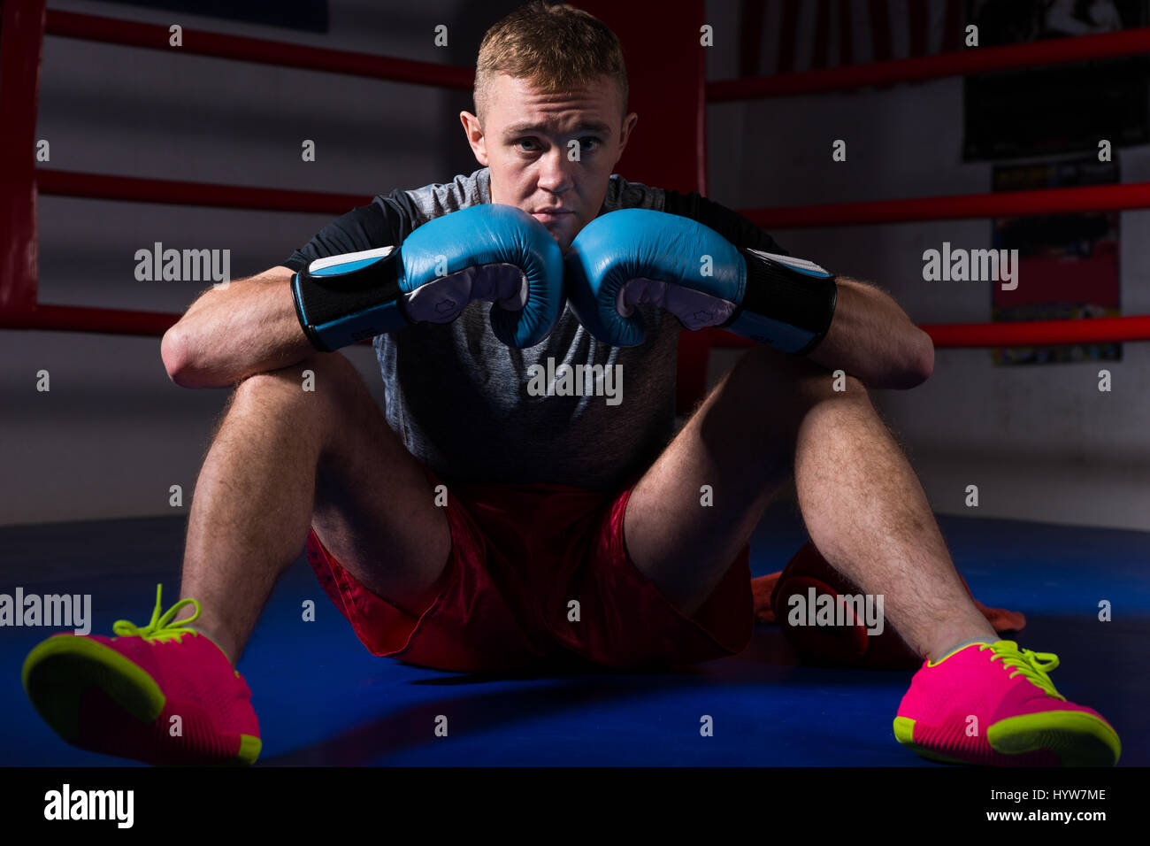 Young male boxer in boxing gloves sitting in regular boxing ring in a ...