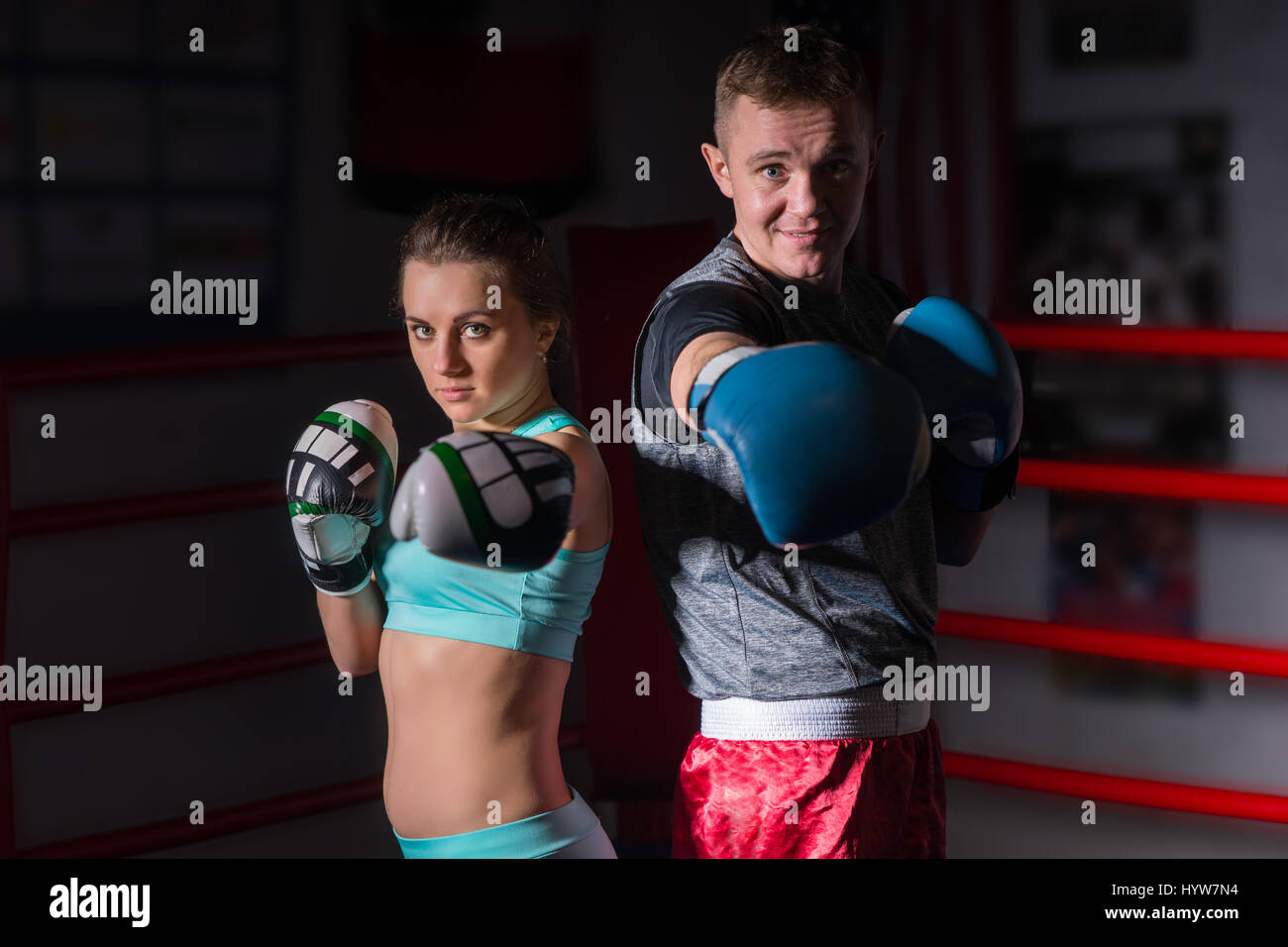 Sporty pair in sportswear and in boxing gloves standing in regular ...
