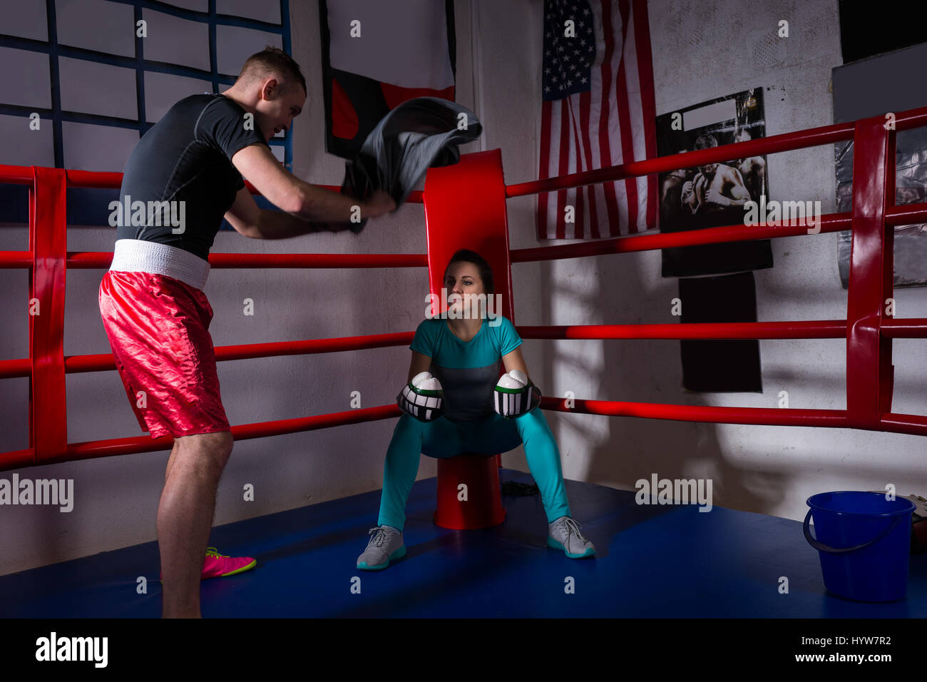 Young sporty female boxer in boxing gloves after battle sitting next ...