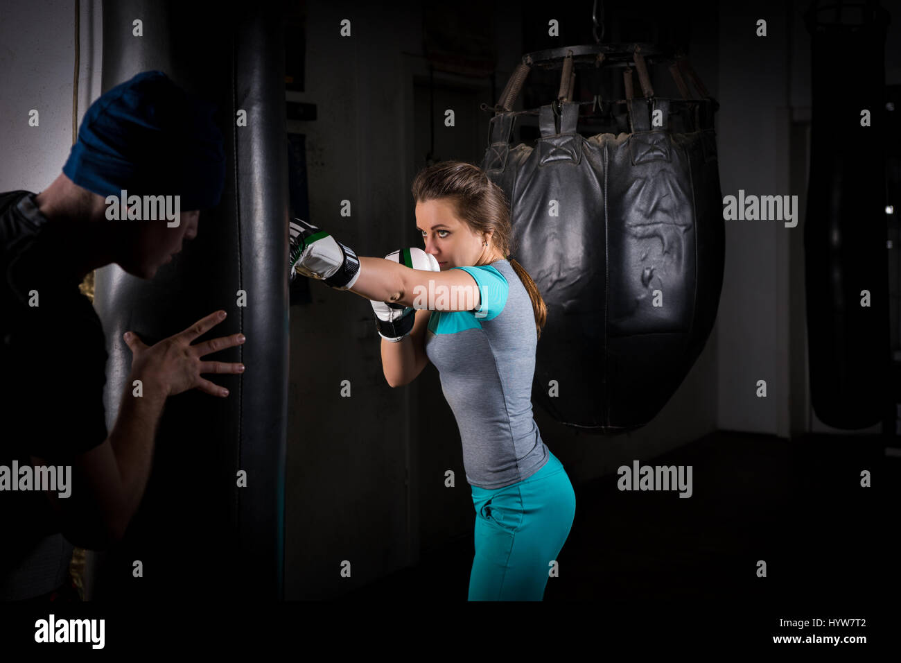 Female sporty boxer in boxing gloves training with her couch and boxing ...