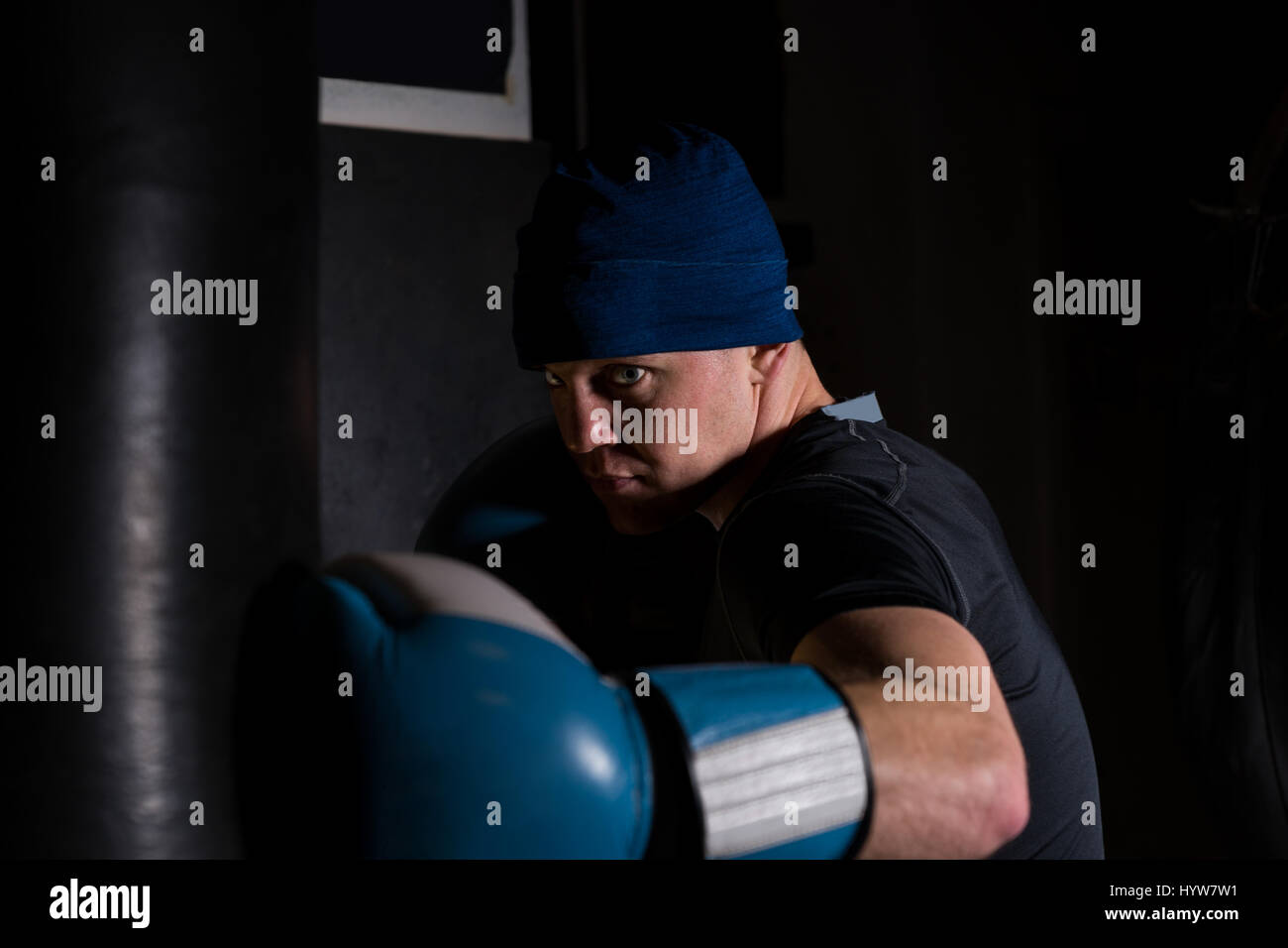 Adult boxer in boxing gloves training with boxing punching bag in a gym ...