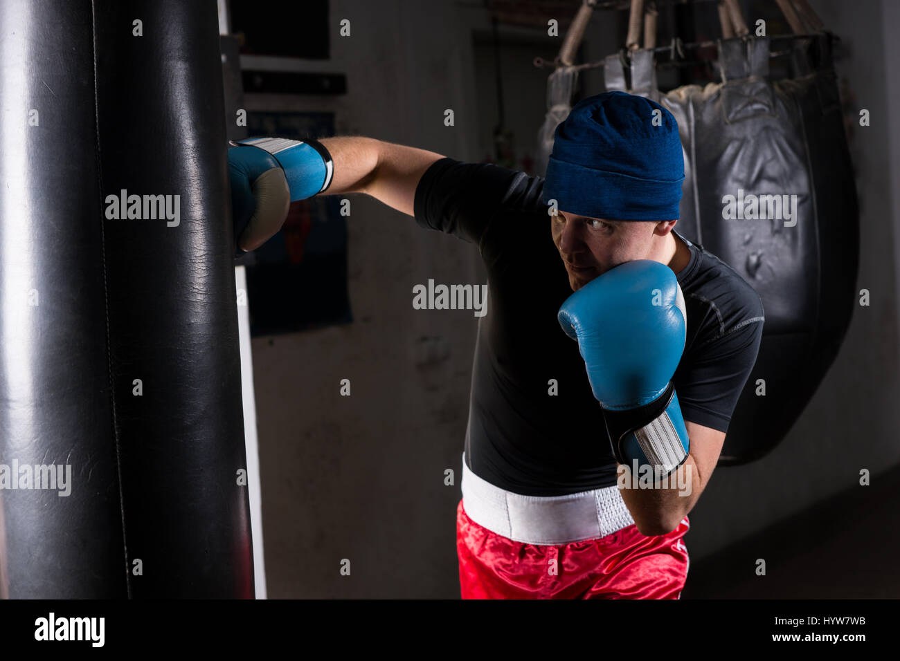 Young sporty man in a hat and boxing gloves training with boxing ...