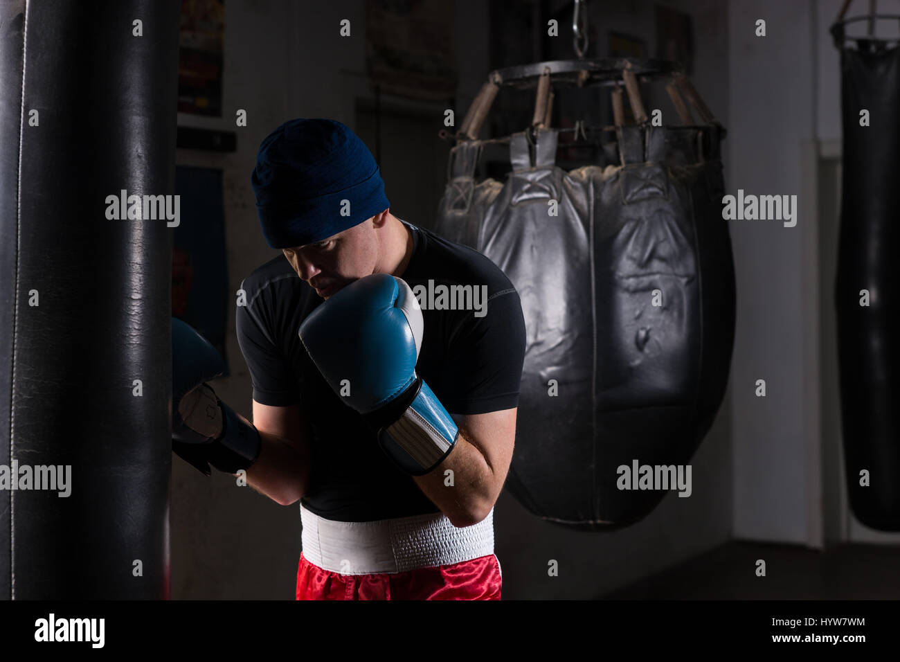 Young male boxer in a hat and boxing gloves training with boxing ...