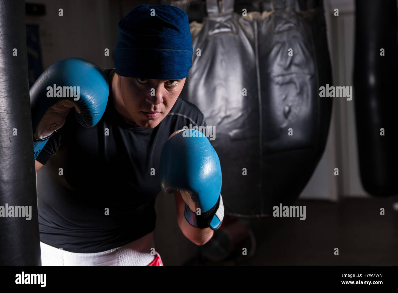 Young male boxer with stern look in a hat and boxing gloves training ...