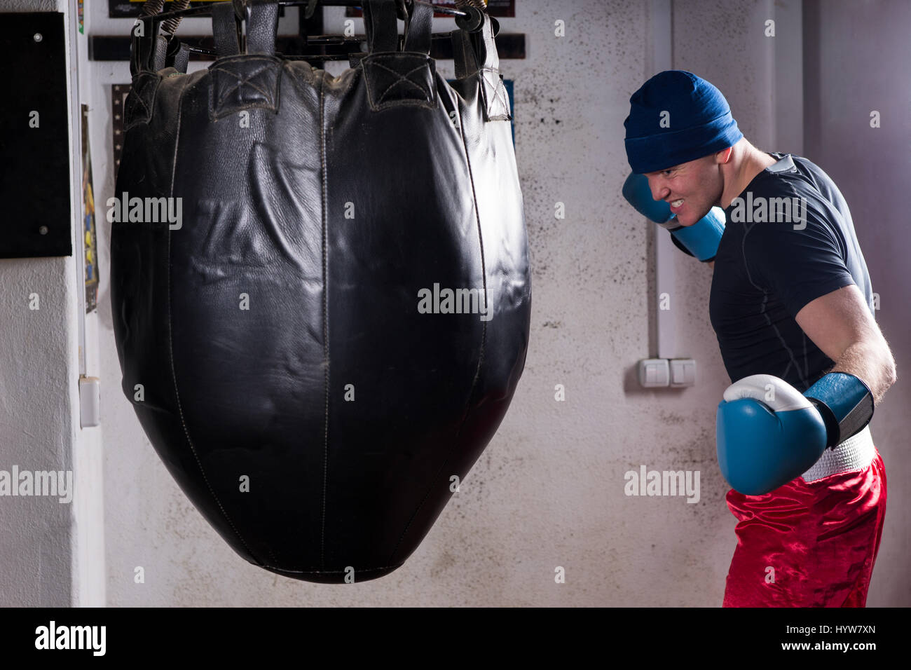 Angry boxer with stern look in a hat and boxing gloves training with ...