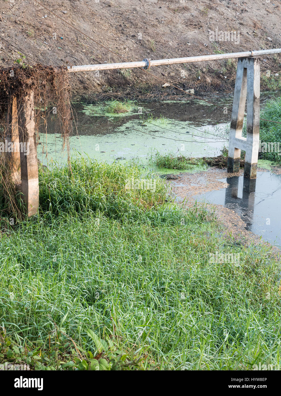 Small steel pipe on the concrete pillar is crossing the stream in the ...