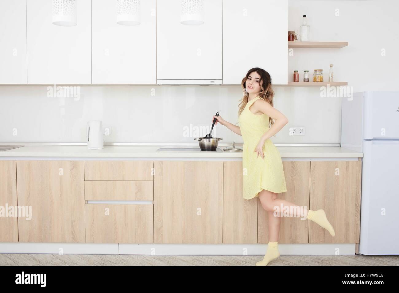 Cooking woman in a yellow dress in kitchen with plastic spoon Stock ...