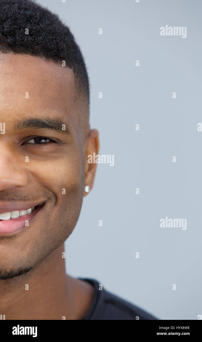 Half face portrait of a smiling man posing against gray background ...
