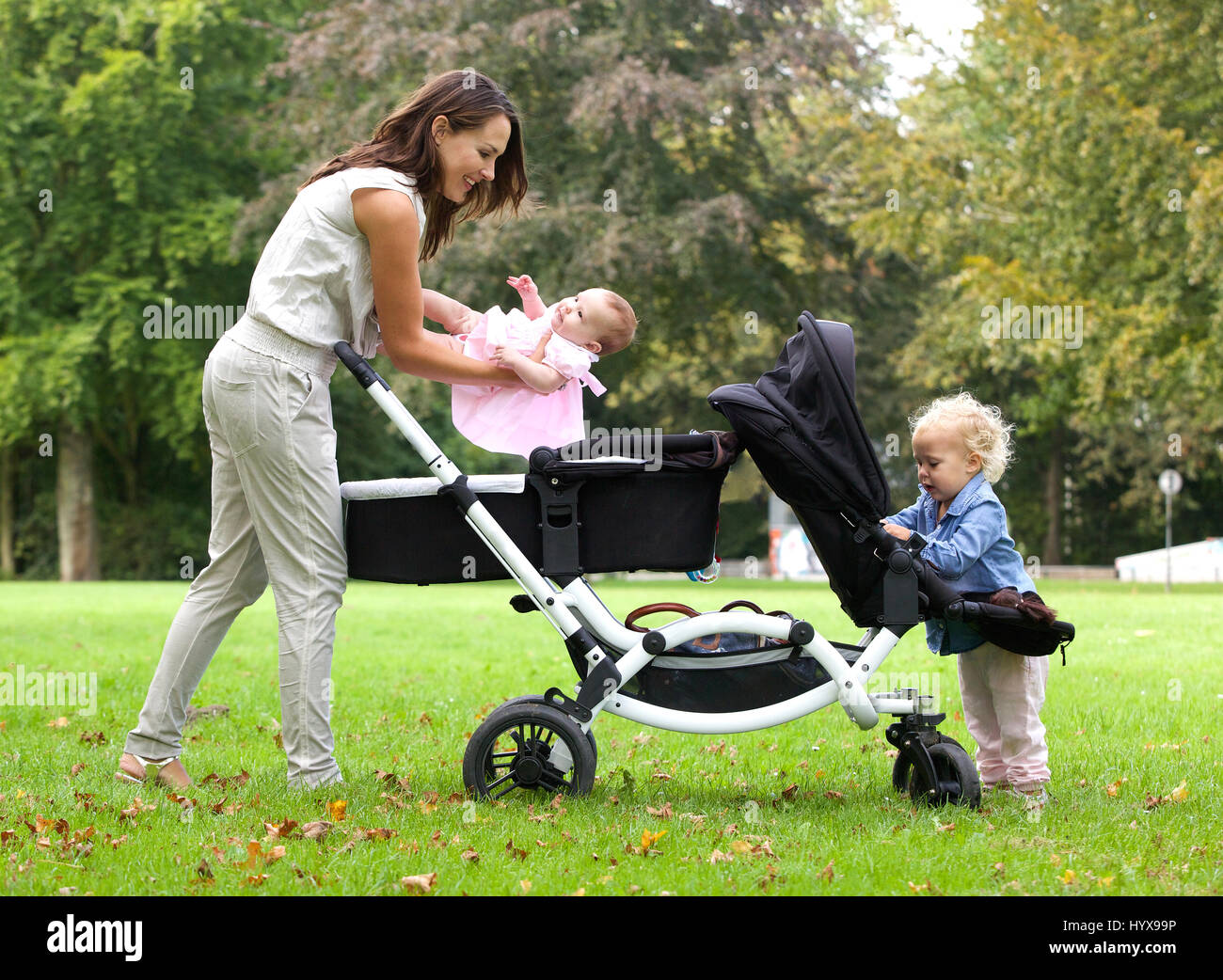 Portrait of a mother and daughters with pram outdoors Stock Photo - Alamy
