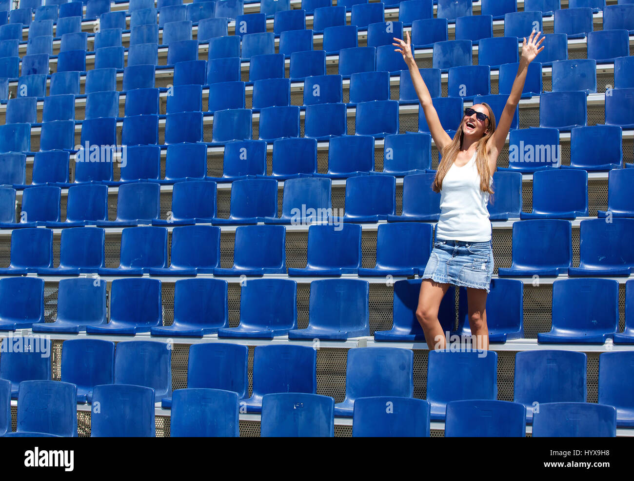 Young woman cheering with arms raised at sporting event Stock Photo - Alamy