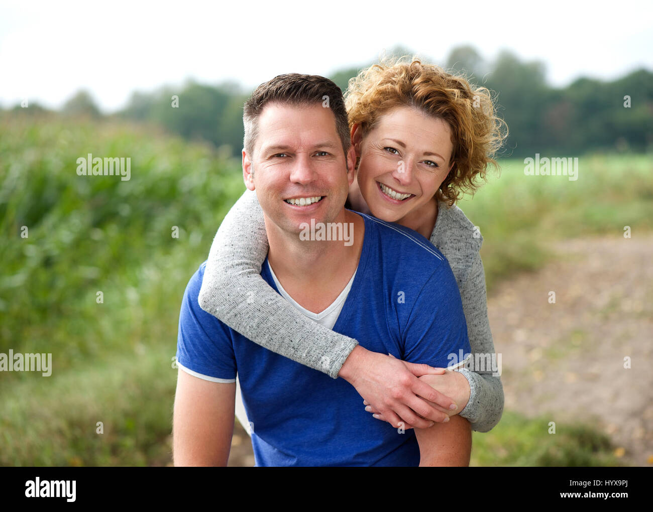 Close up portrait of a smiling woman hugging her boyfriend outdoors Stock Photo - Alamy