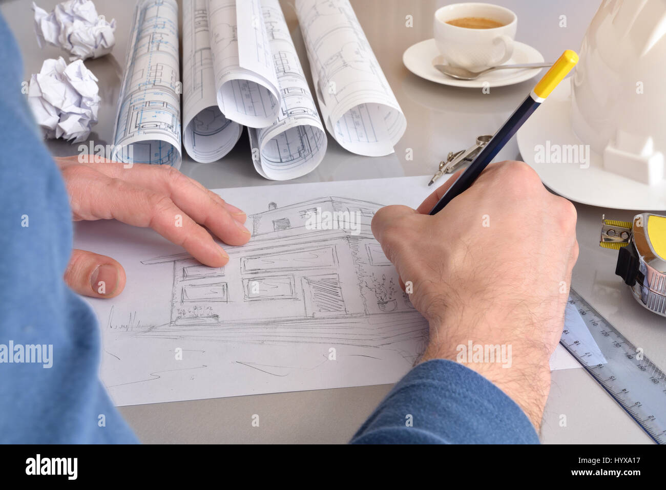 Construction engineer drawing a house on his office desk close up. With ...