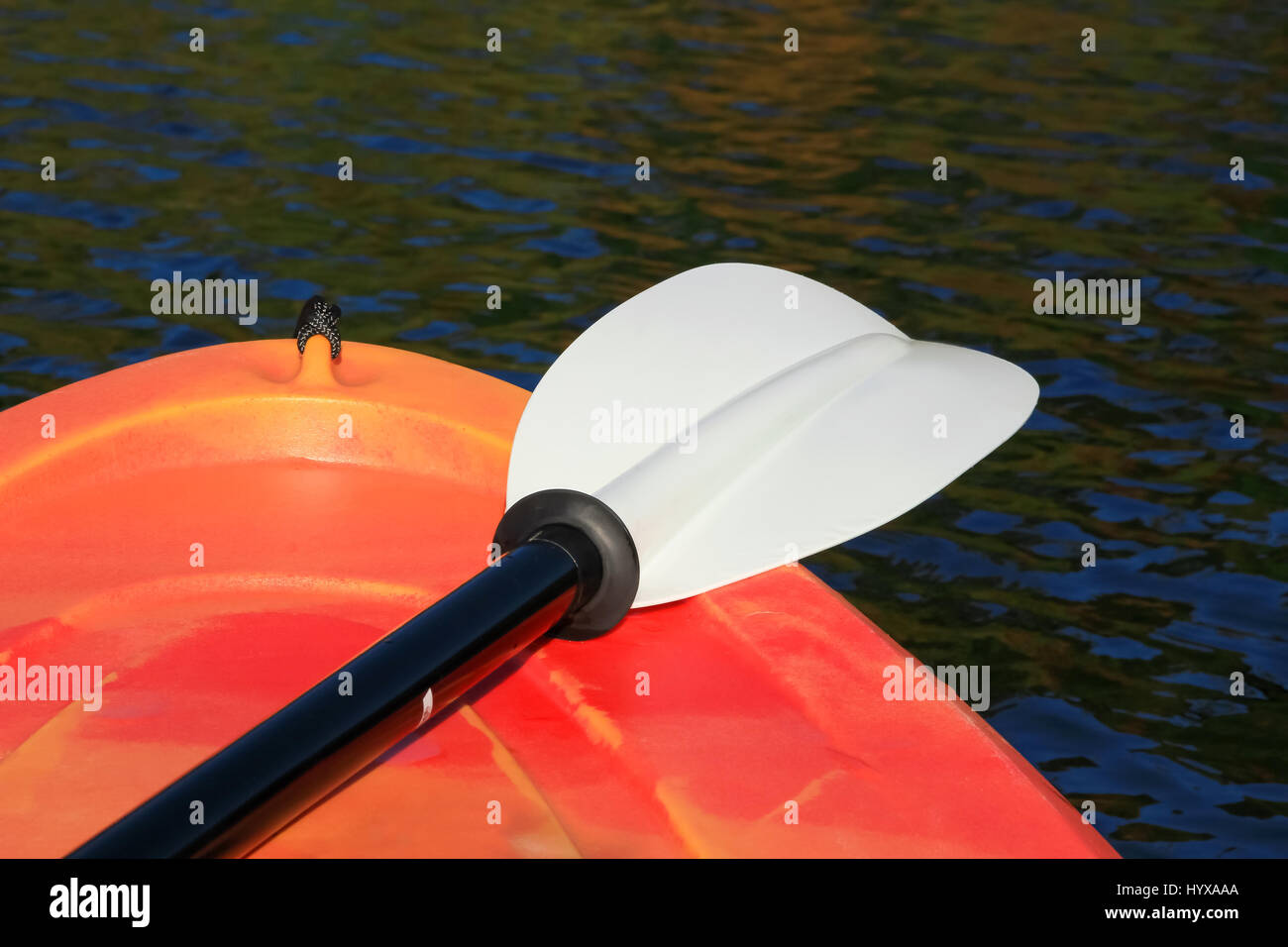 Bright orange kayak and paddle on the water with colorful reflections ...