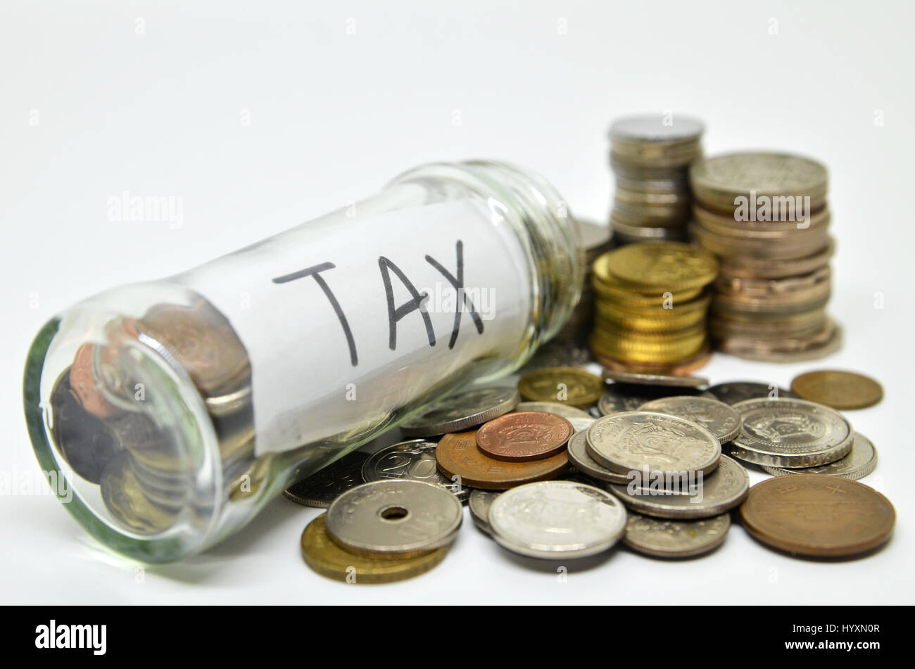 Tax lable in a glass jar with coins spilling out isolated on white ...