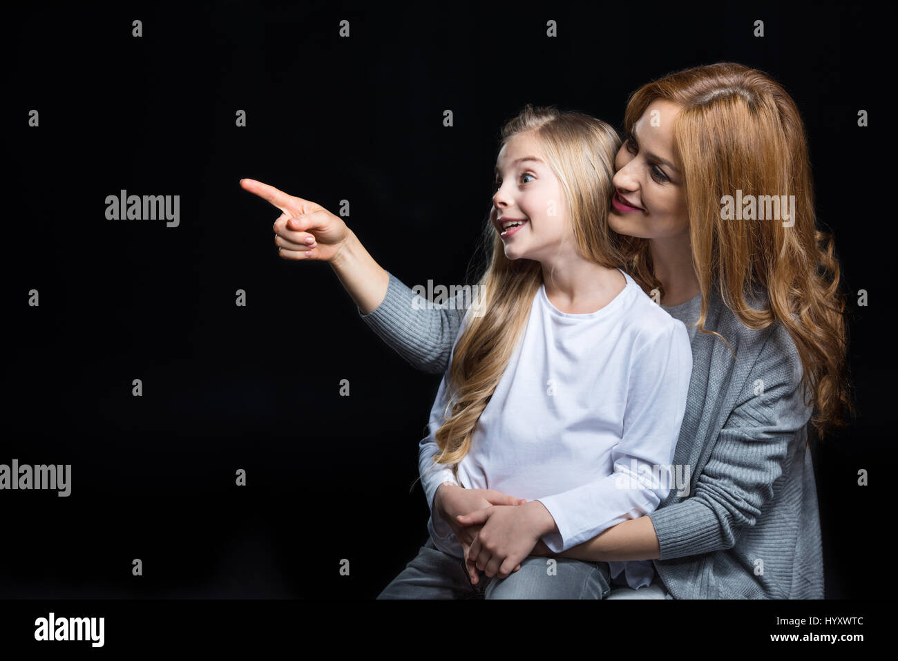 Young mother pointing and showing something to her little daughter on ...