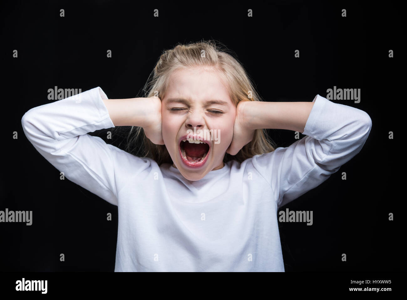 Little girl screaming and covering her ears with hands on black Stock ...
