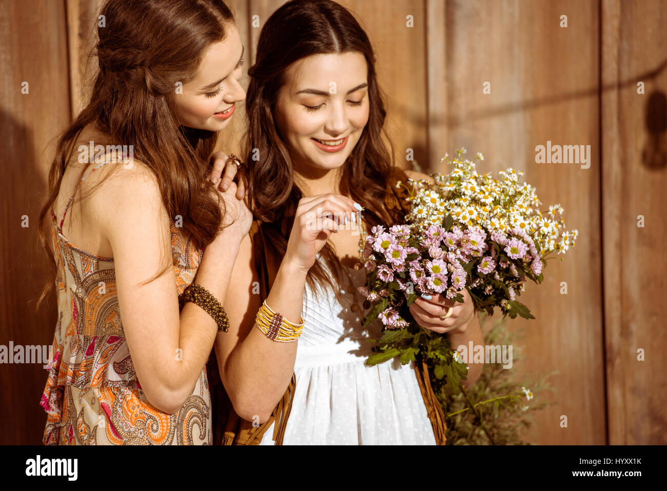 Two attractive young hippie women standing with flowers and smiling ...